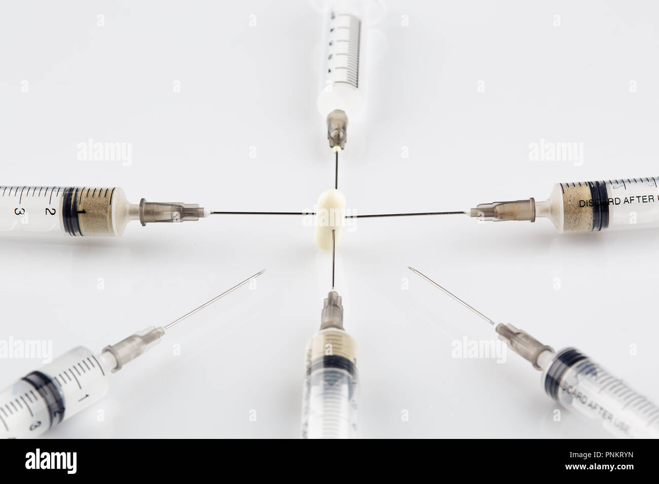 Many syringes pierce a white capsule Stock Photo - Alamy