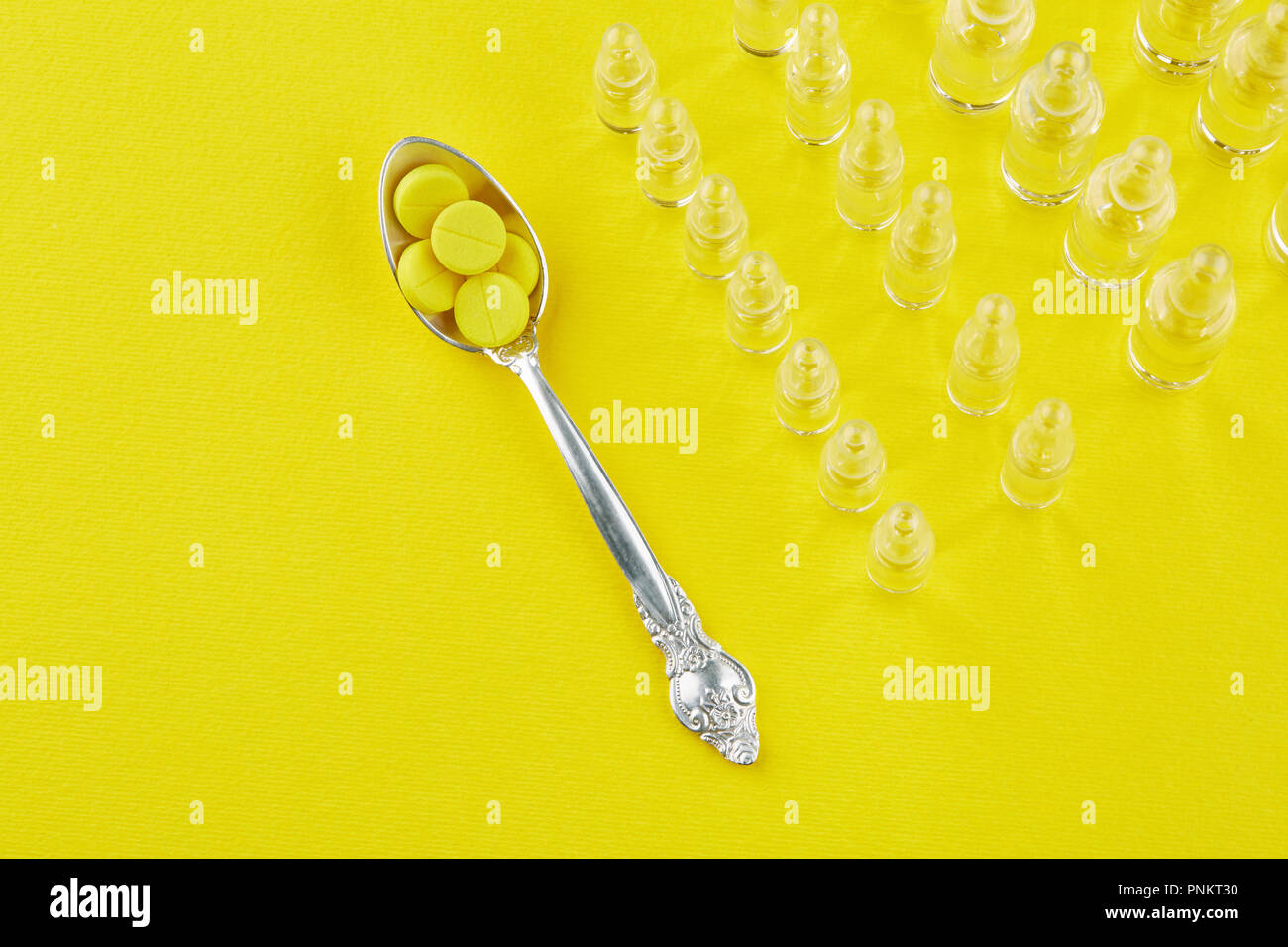 Spoon with tablets and ampoules on yellow background Stock Photo - Alamy
