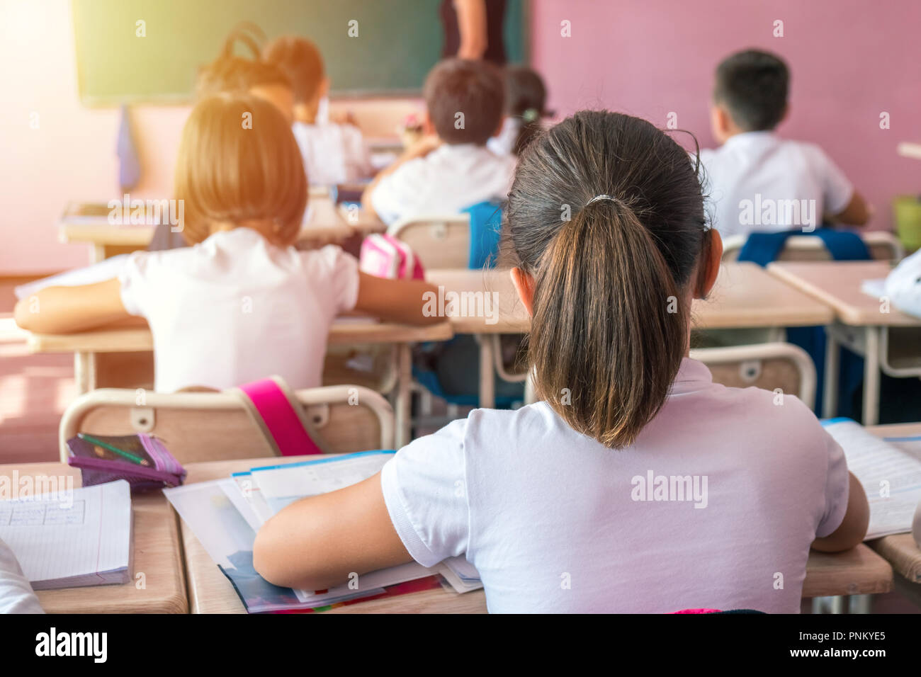 group of school kids sitting and listening to teacher in classroom from ...