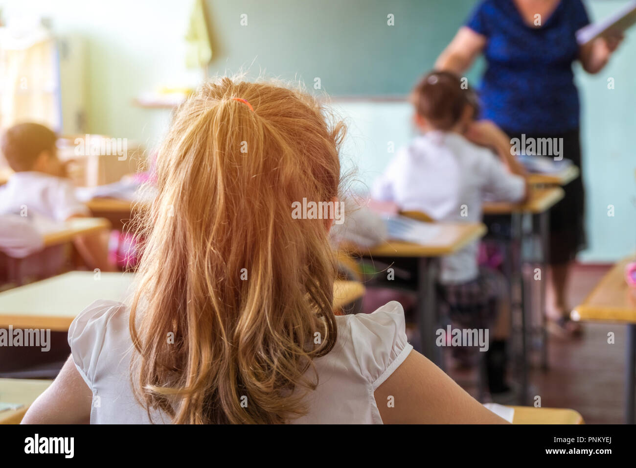 group of school kids sitting and listening to teacher in classroom from ...