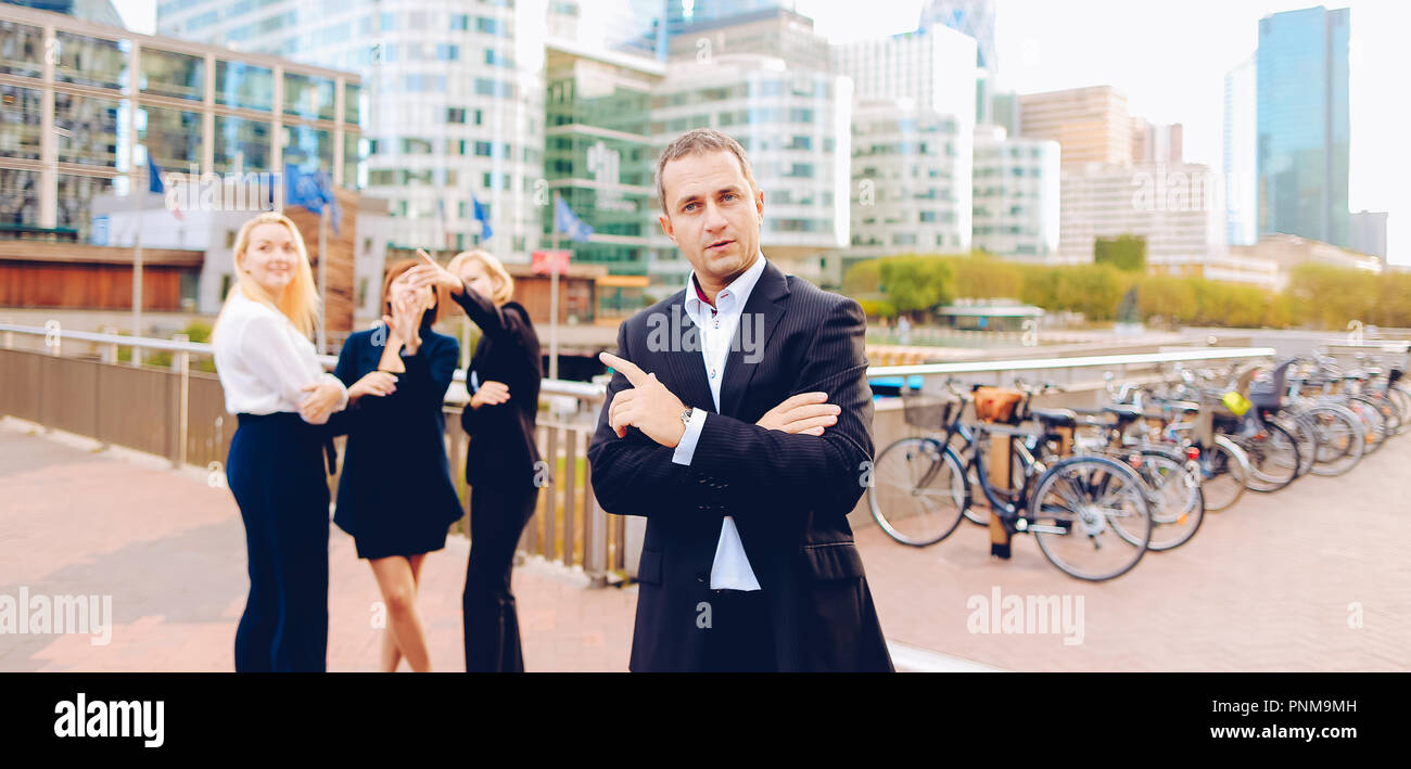 Male boss looking at watch near employees talking in background ...