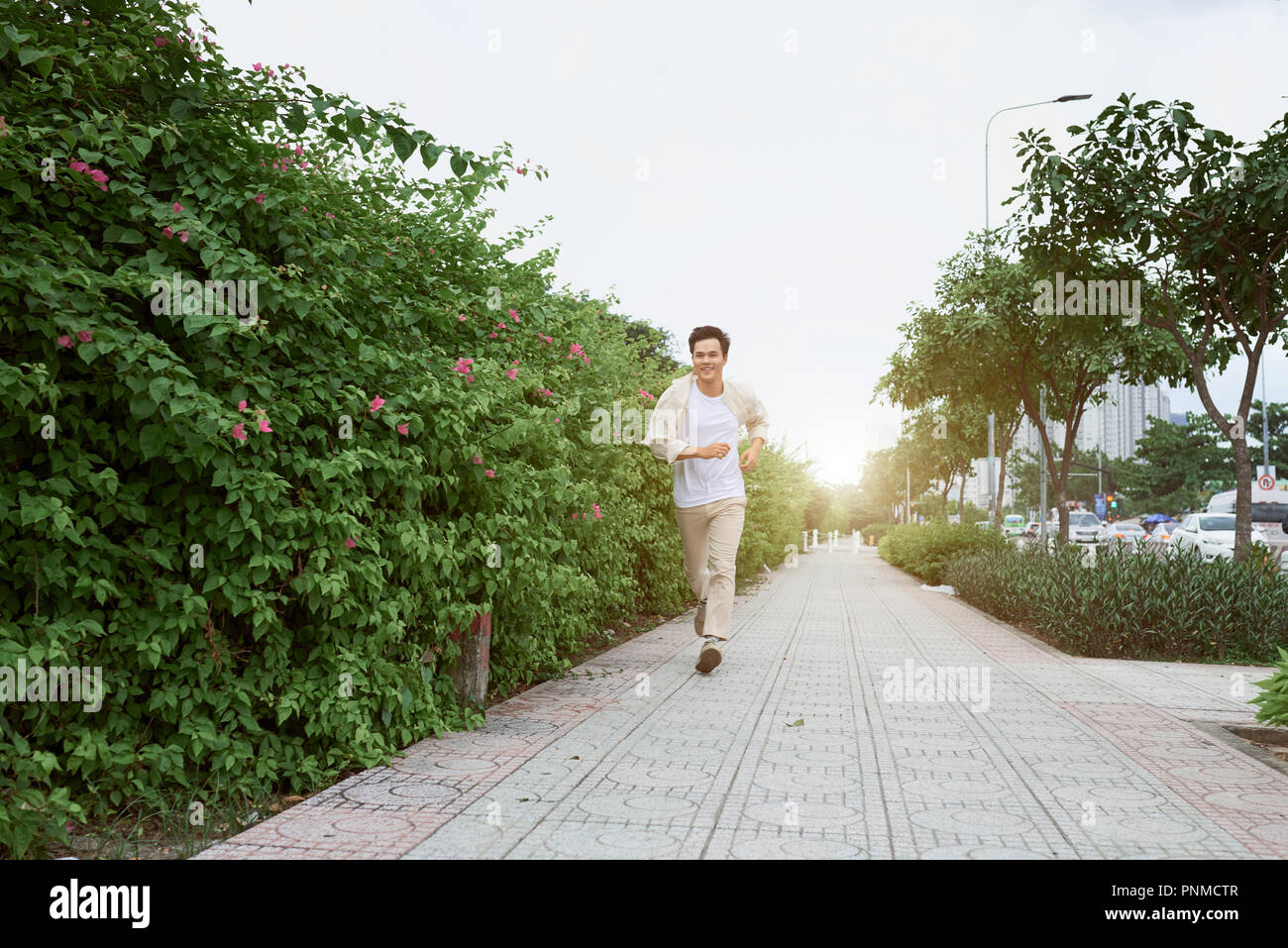 Smiling young man running in the park during summer Stock Photo - Alamy