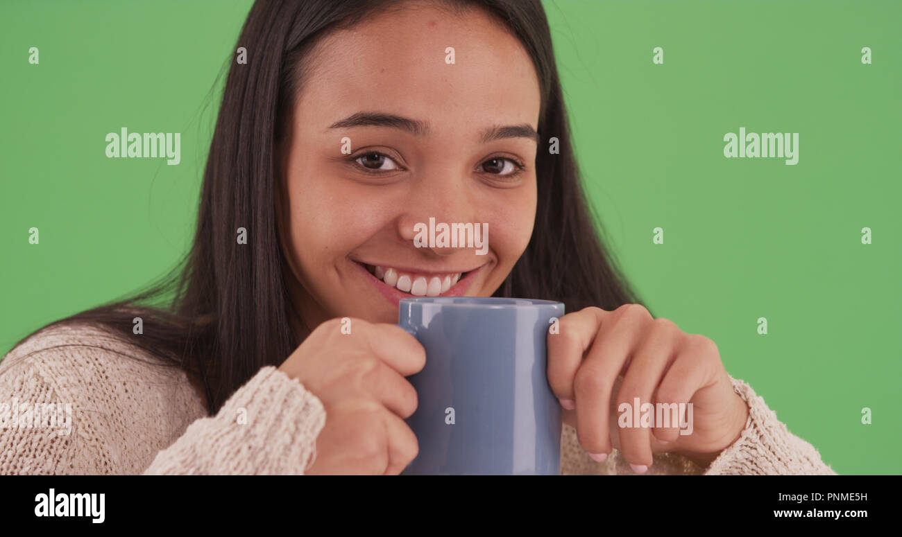 Millennial latina girl smiles while she thinks about her hot tea on ...