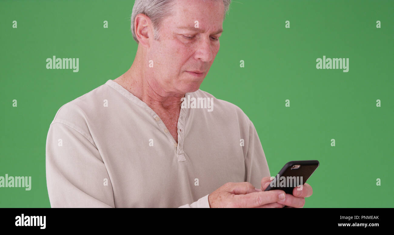 Portrait of a mature white man texting in front of green screen Stock ...