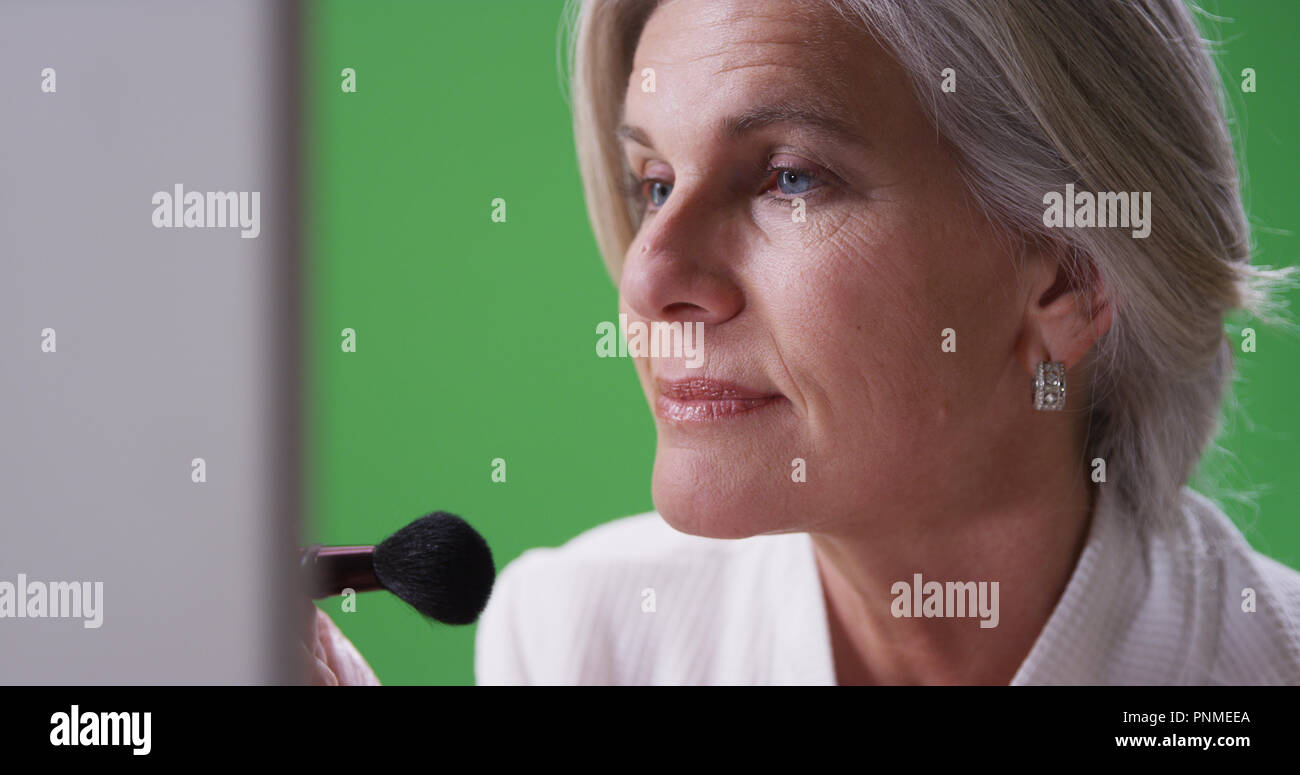 Lovely mature caucasian woman applying makeup on greenscreen Stock ...