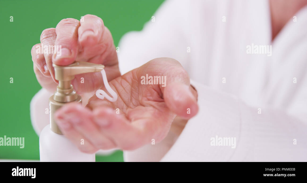 Senior caucasian woman applying lotion to hands on greenscreen ...