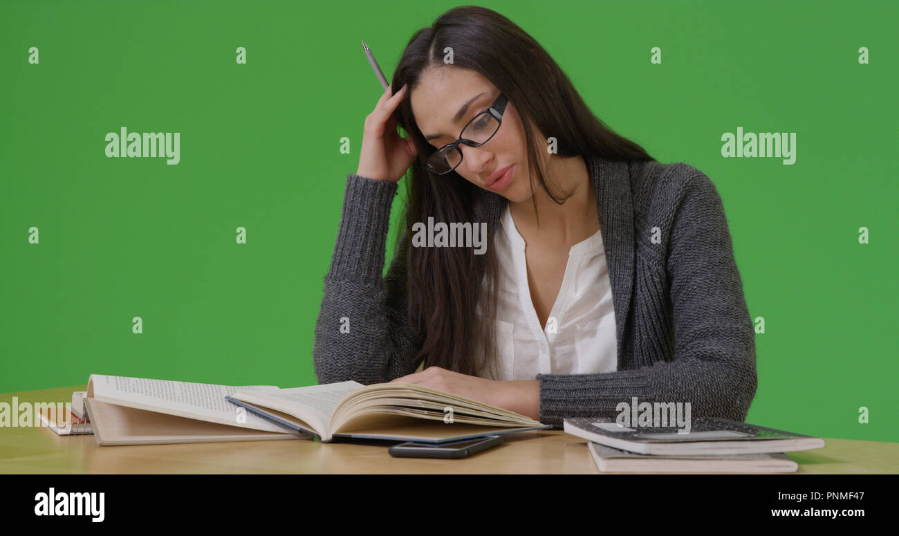 Latina college student does her homework at her desk on green screen ...