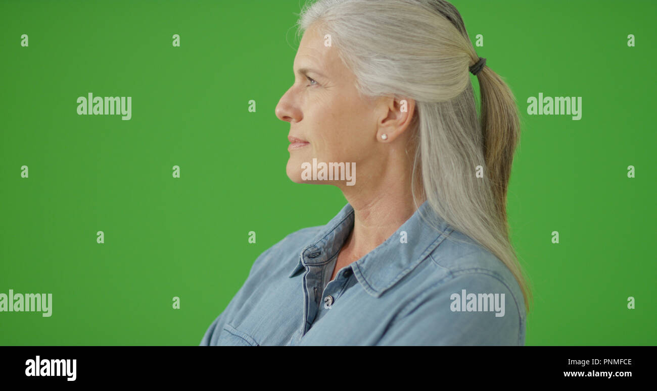 Proud looking senior woman looking off into distance on green screen ...
