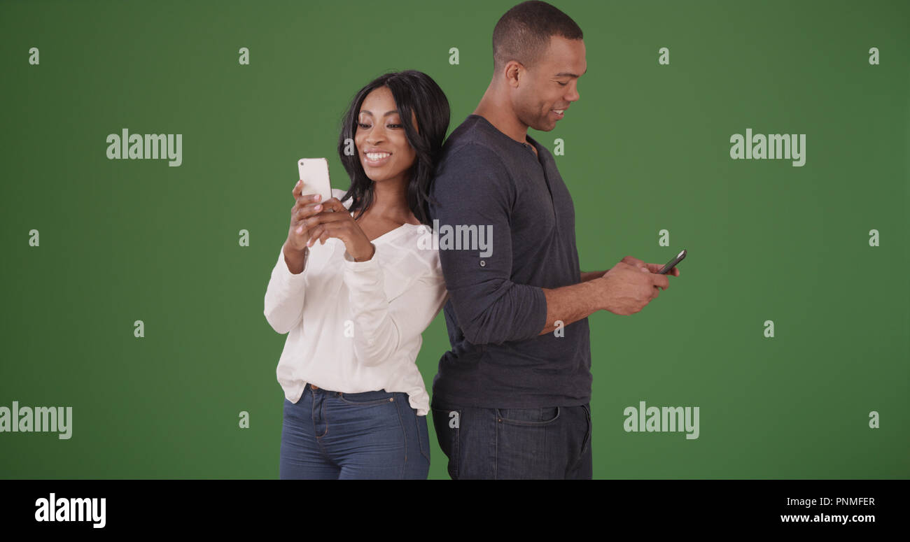 Couple standing back to back texting on cell phones on green screen ...