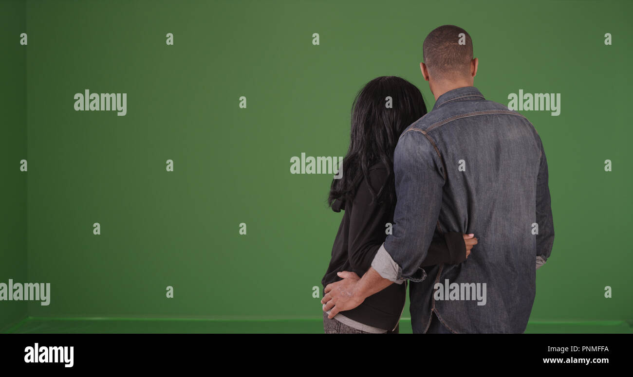 Intimate black boyfriend and girlfriend with back to camera on green ...