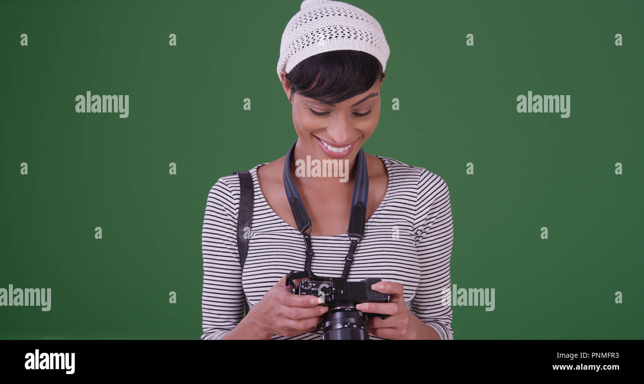 Woman with camera looking through photos and looking around on green ...