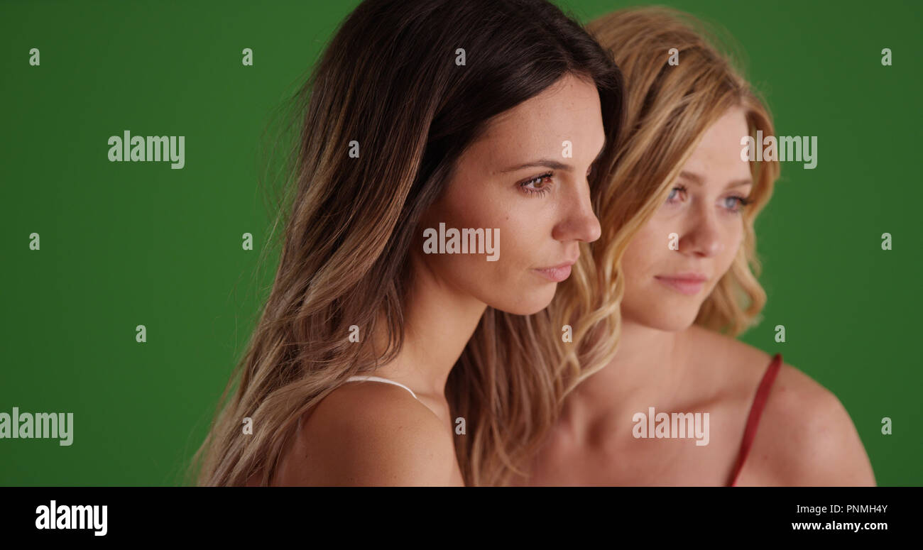 Portrait of two beautiful white women looking off screen on green ...
