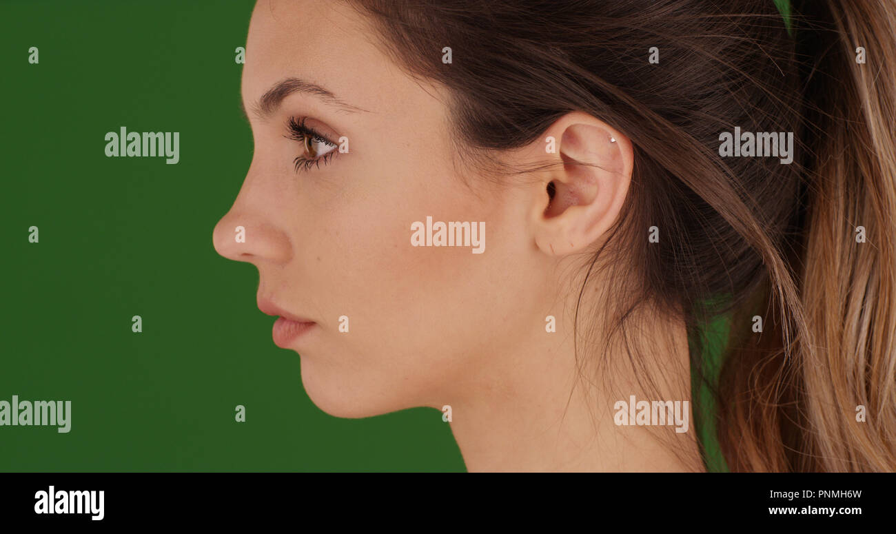 Close-up side profile of beautiful female model posing on green screen ...