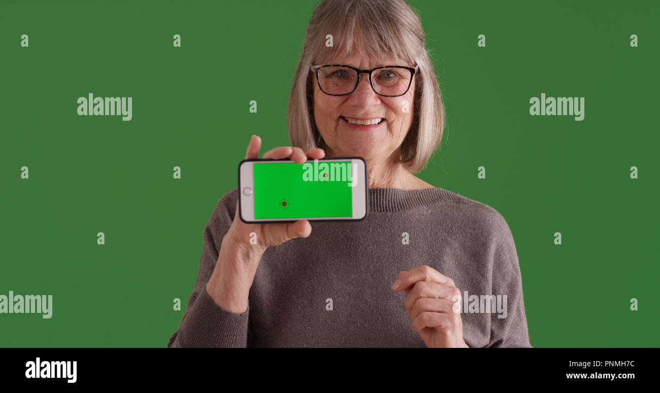 Old white lady showing phone display with green screen to camera on ...