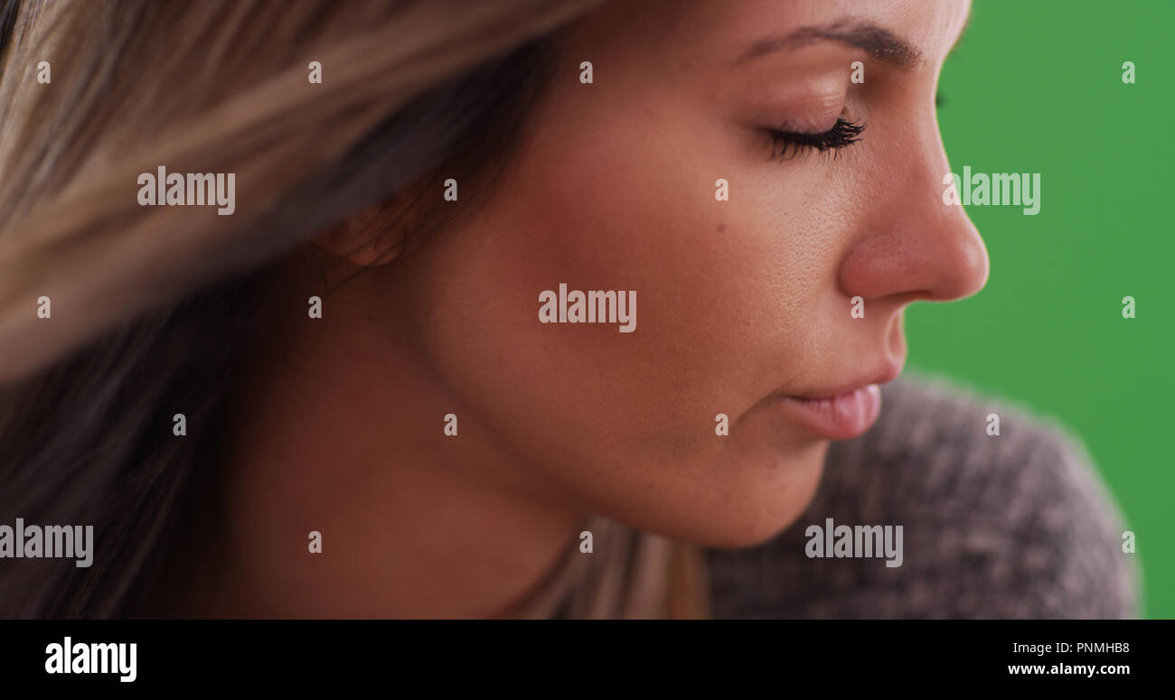 Tight shot of attractive young woman with eyes closed thinking on green ...