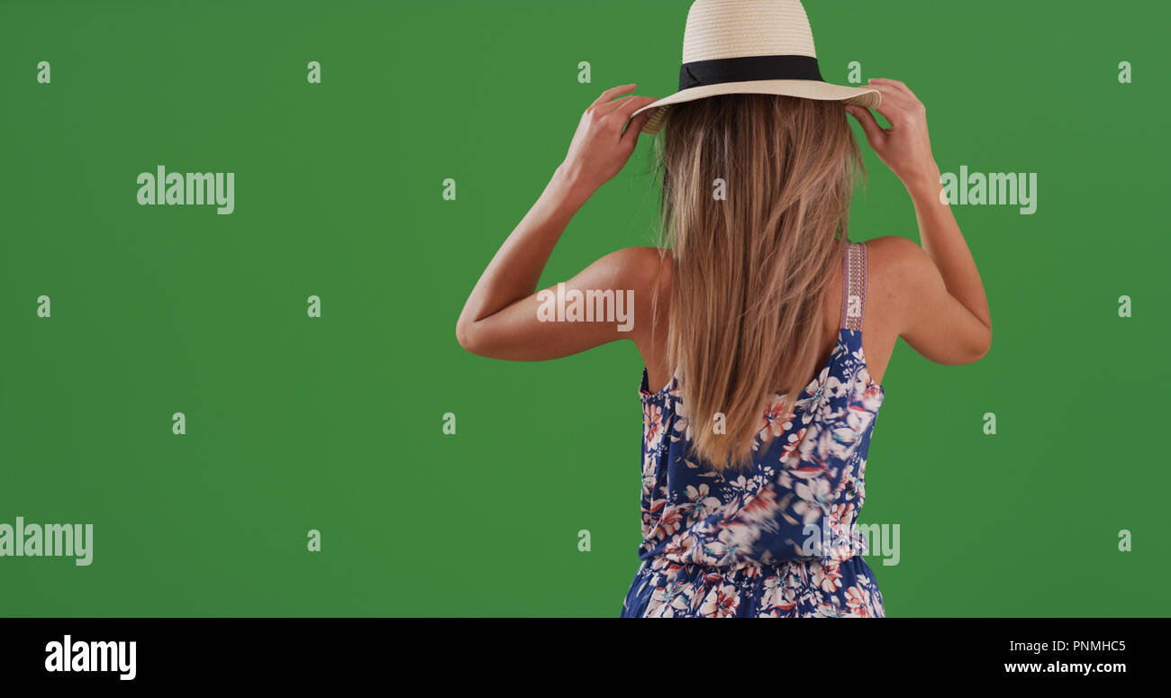 Rear view of young white woman in fedora and romper on green screen ...