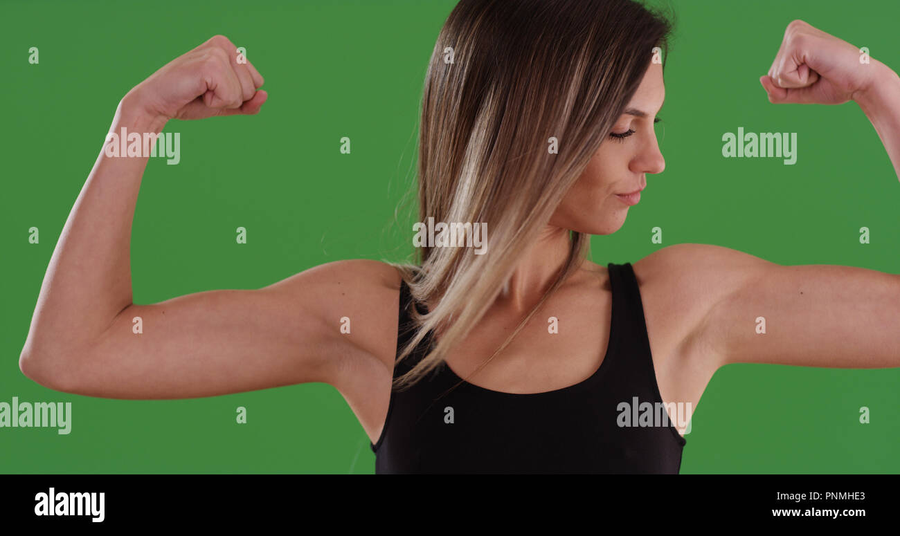 Athletic Caucasian female flexing biceps for camera on green screen ...
