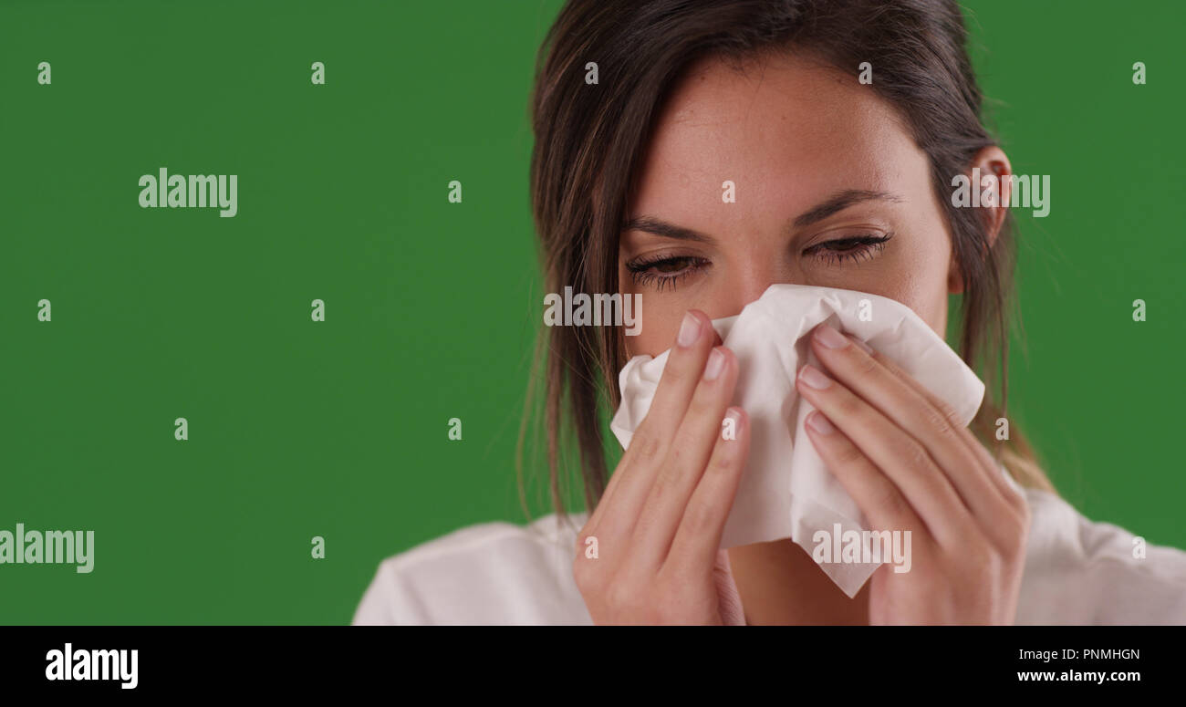 Sick Caucasian woman blowing nose into tissue paper on green screen ...