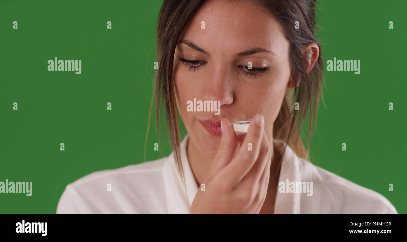 Sick Caucasian woman with a fever using thermometer on green screen ...