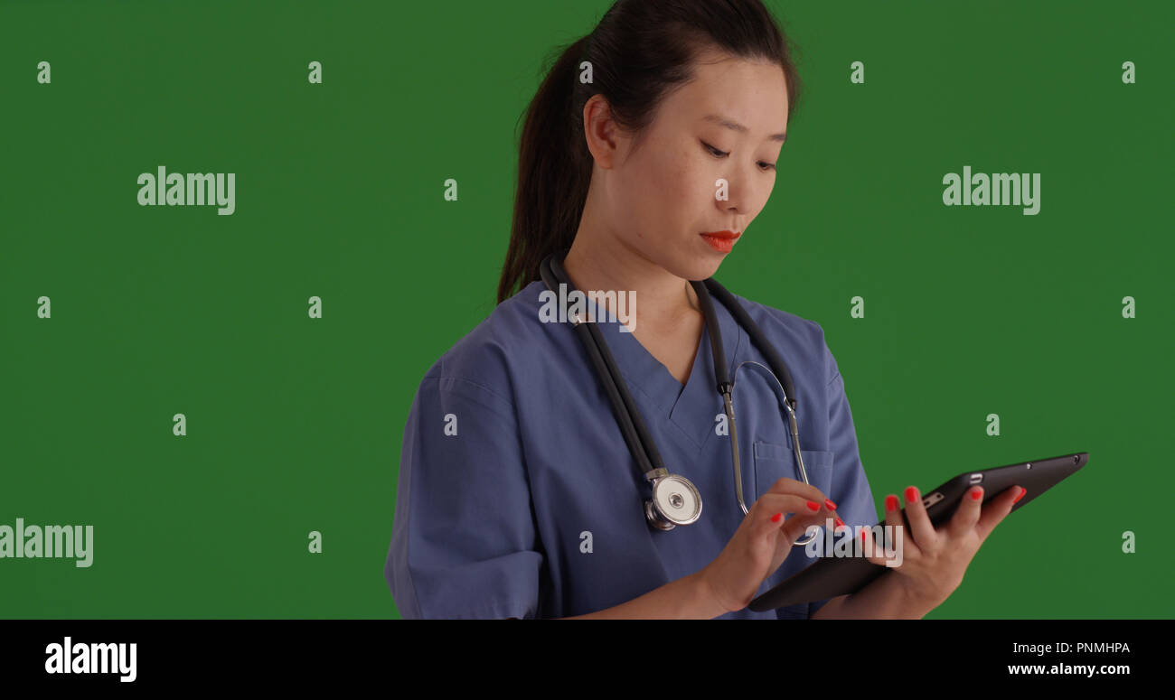 Portrait of young medical assistant using portable tablet on green ...