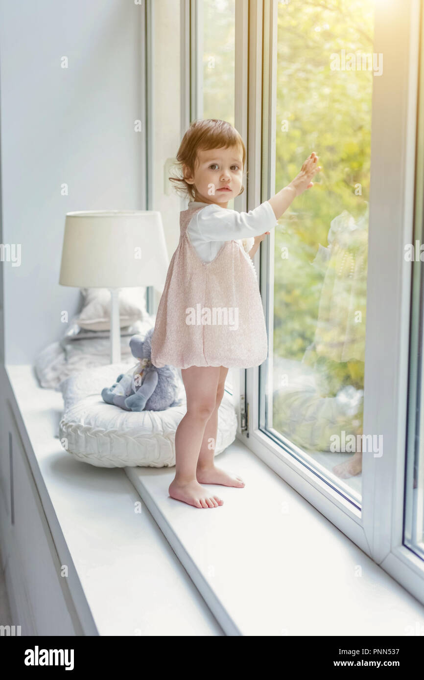 Little cute sweet smiling girl in pastel pink dress standing on the ...