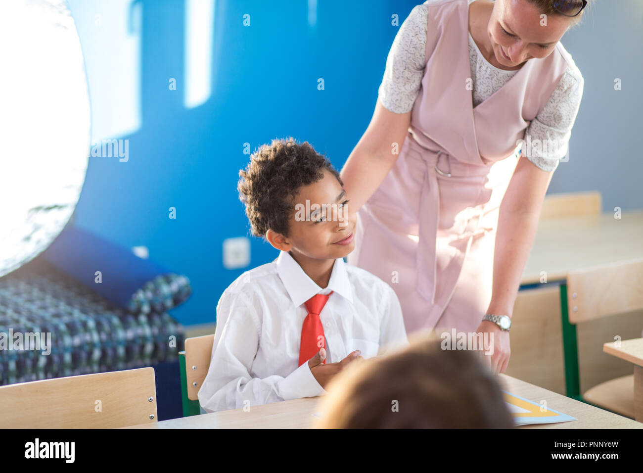 Teacher helping kids with their homework in classroom at school Stock ...