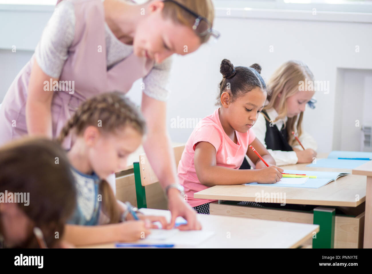 Teacher helping kids with their homework in classroom at school Stock ...