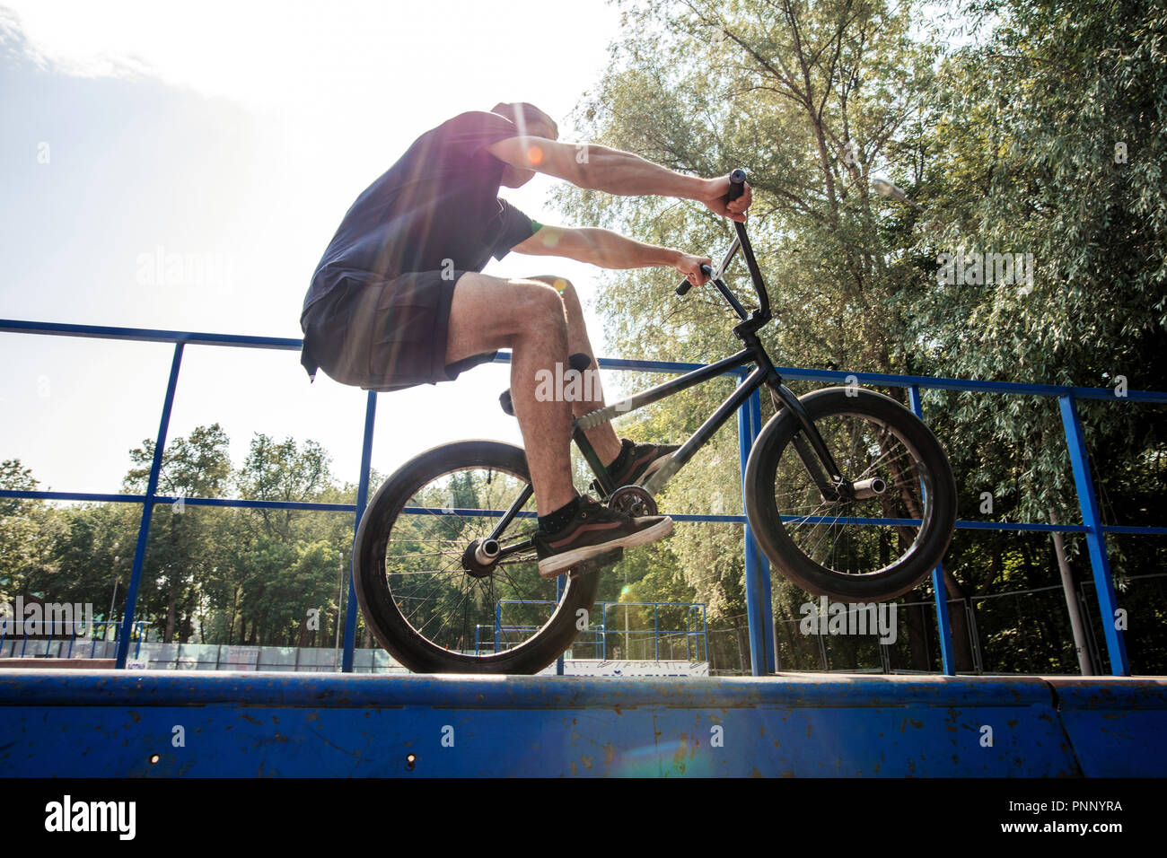 man rides bike onback wheel of BMX. male rider makes tricks on BMX bike ...