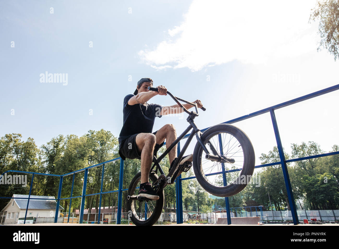 man rides bike onback wheel of BMX. male rider makes tricks on BMX bike ...