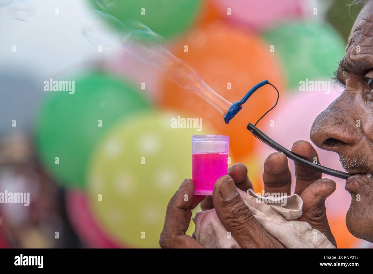 Old man blows bubbles as he sells toys at along the roadside Stock ...