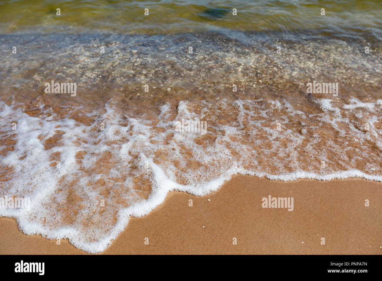 Sea water hitting the sandy shore Stock Photo - Alamy