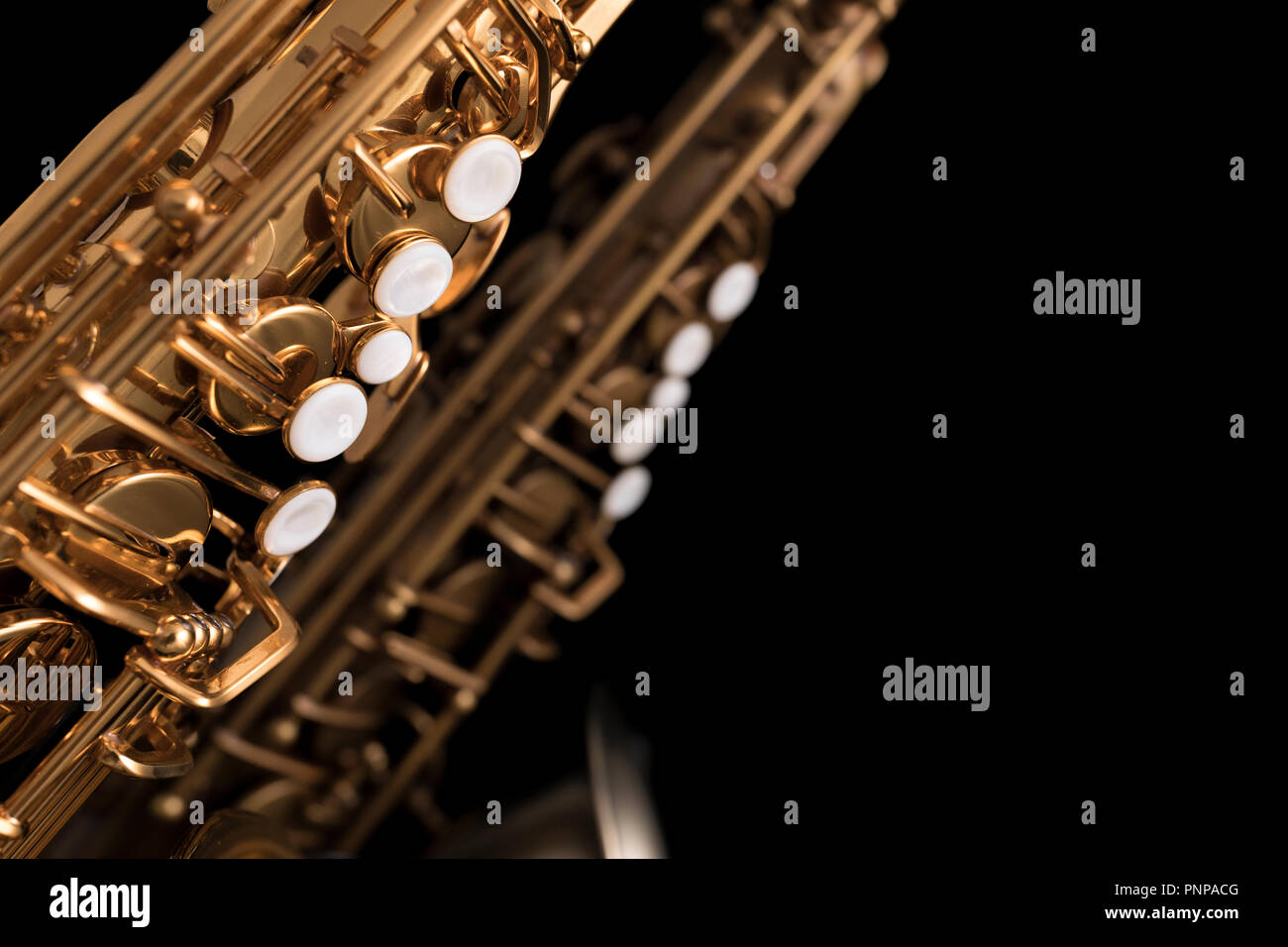 Gold lacquered and matte finish saxophones with pearl keys on black ...