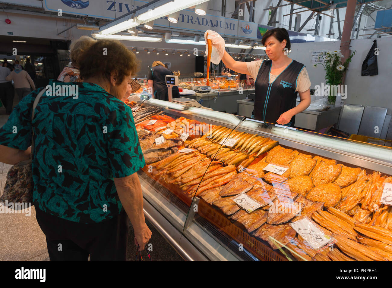 Riga Market, view of a woman behind a smoked fish stall serving a ...