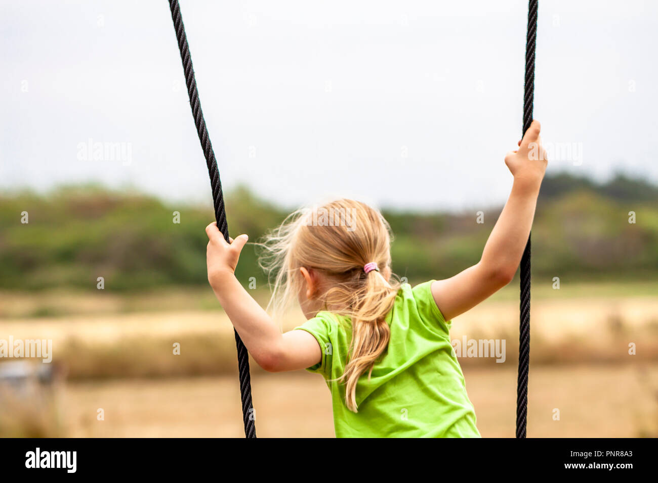 Little girl having fun standing on outdoor swing Stock Photo - Alamy