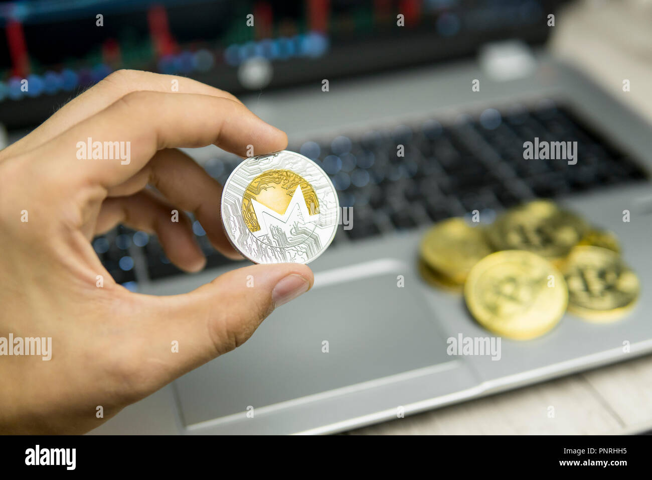 Male businessman hand holding Monero coin on a background of laptop ...