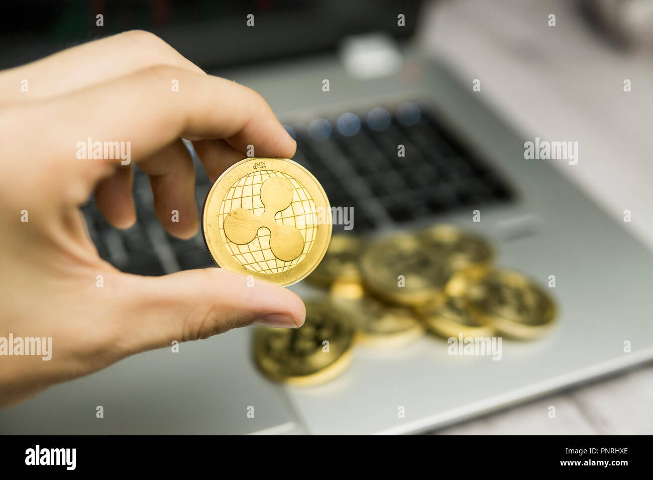 Male businessman hand holding Ripple coin on a background of laptop ...