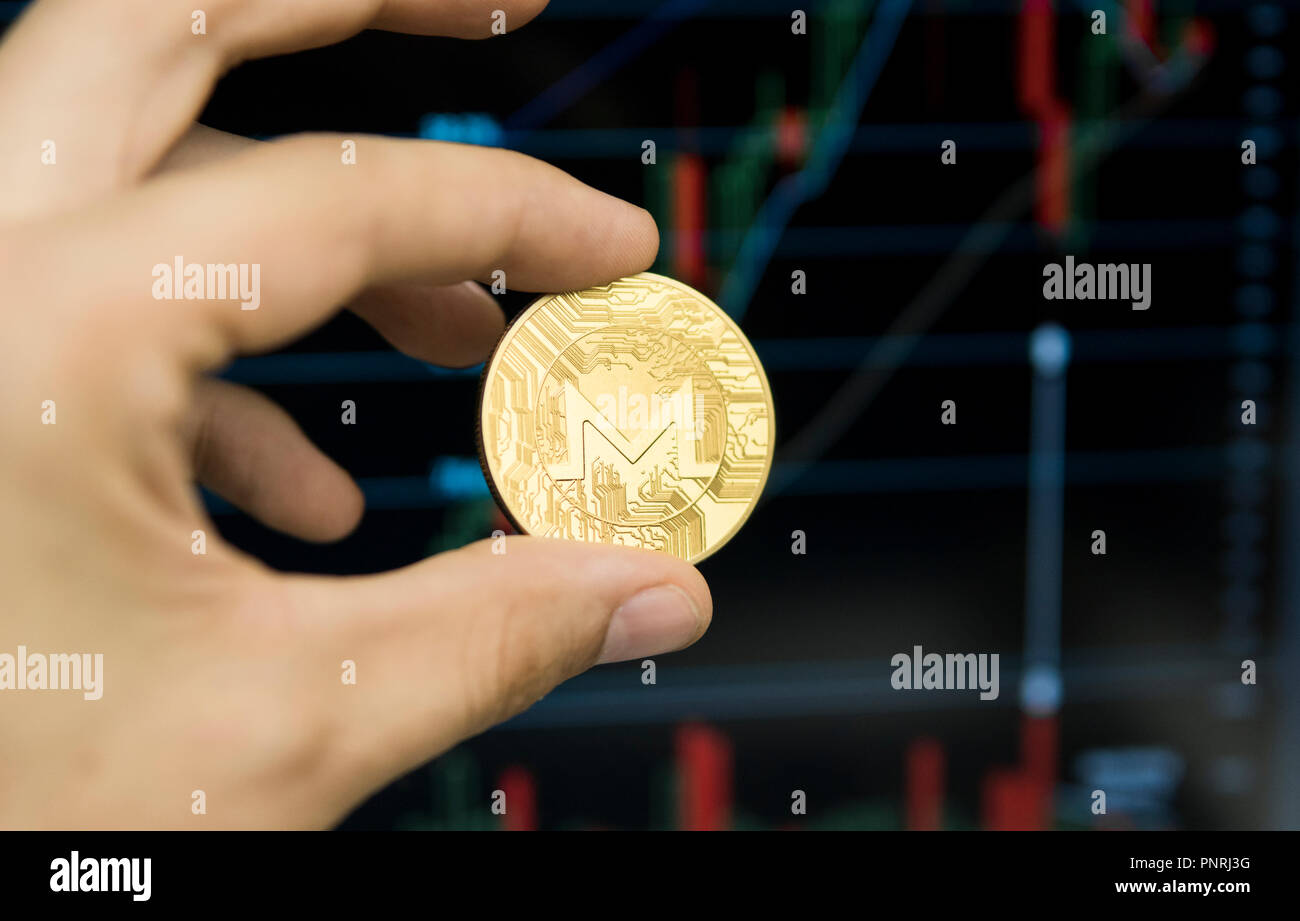 Male businessman hand holding Monero coin on a background of growth ...