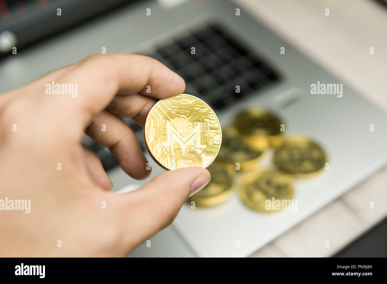 Male businessman hand holding Monero coin on a background of laptop ...