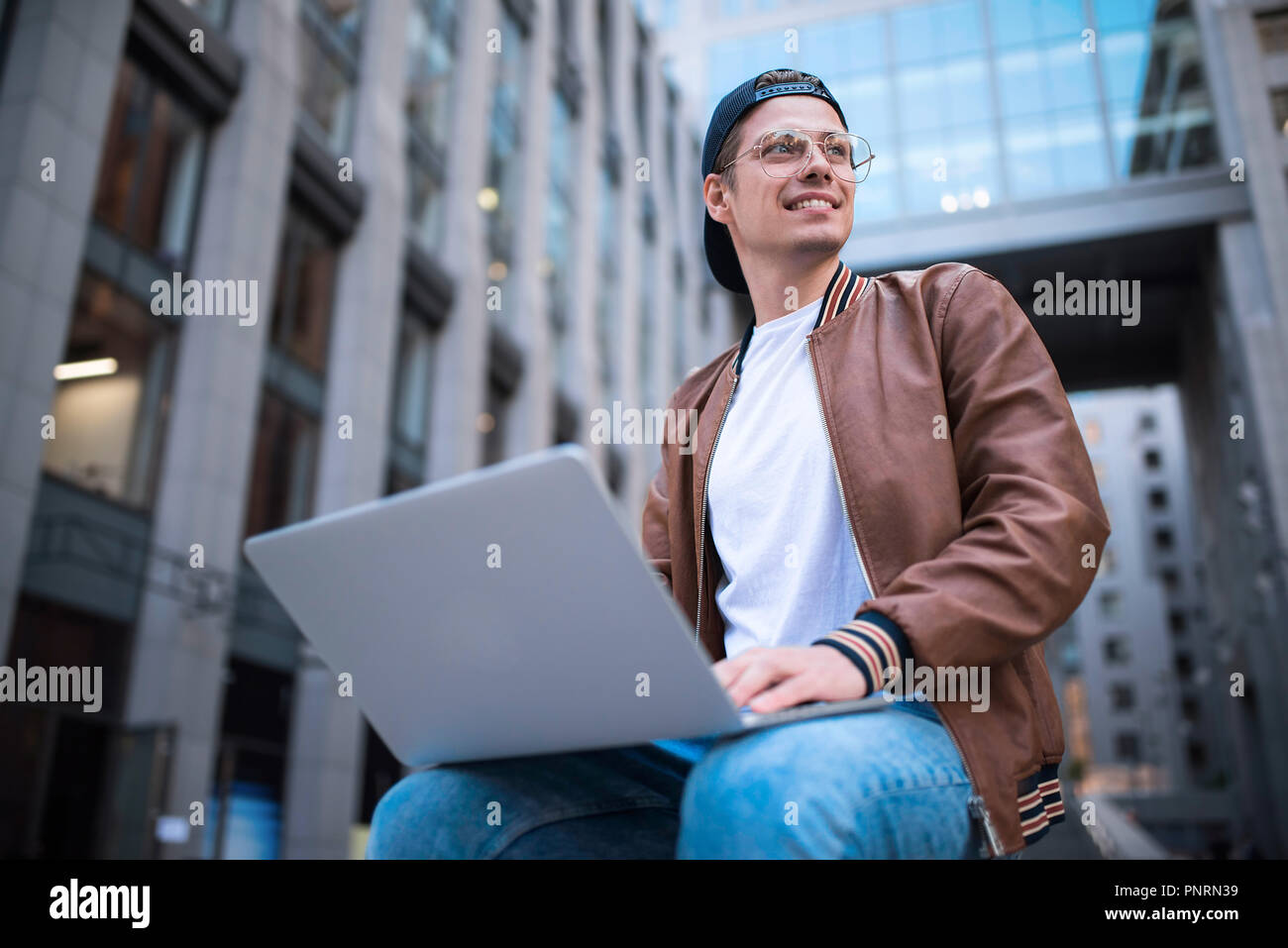 Happy handsome student looking at computer screen while typing ...