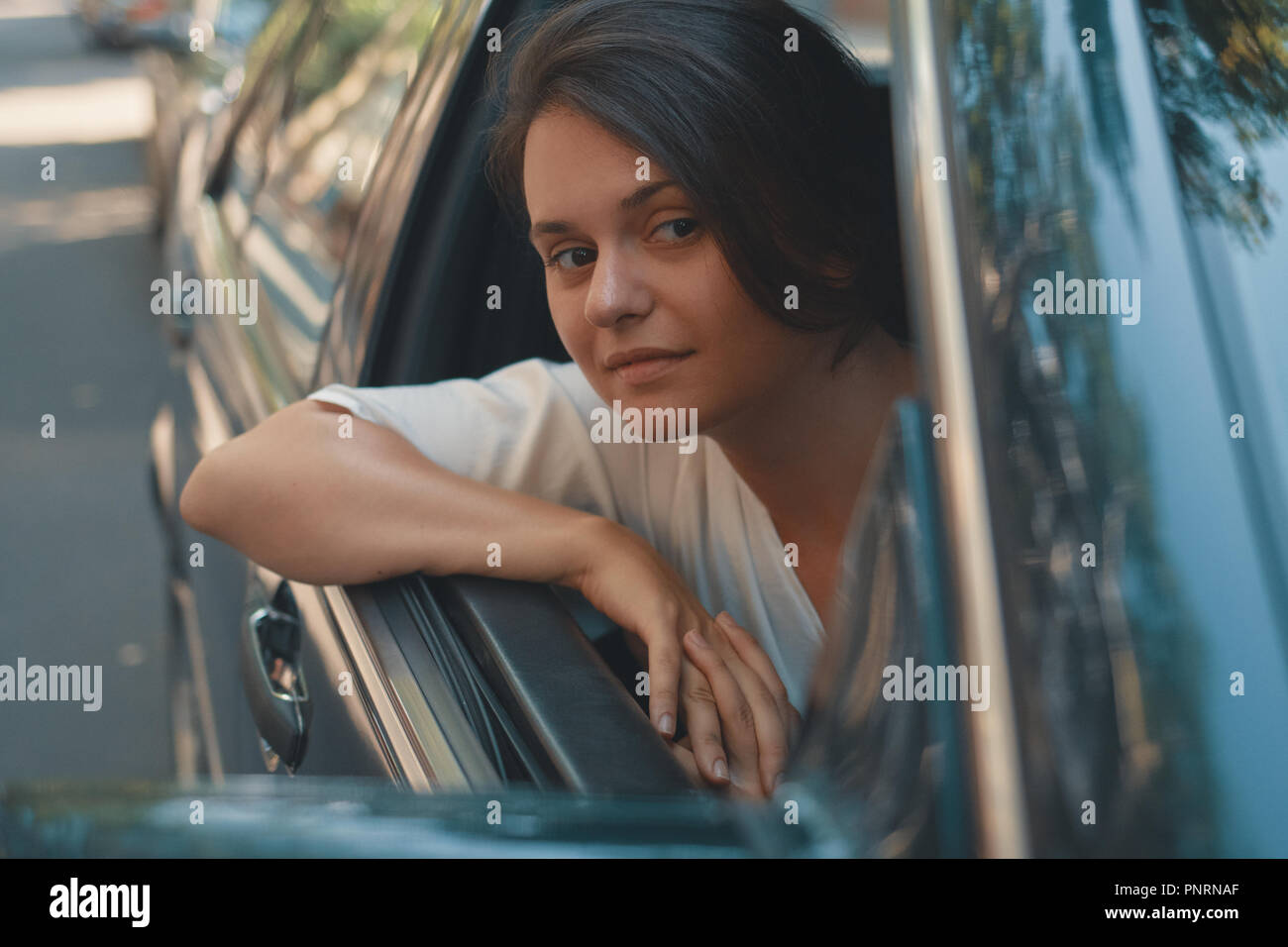 View of attractive young woman in casual wear put head out of window ...