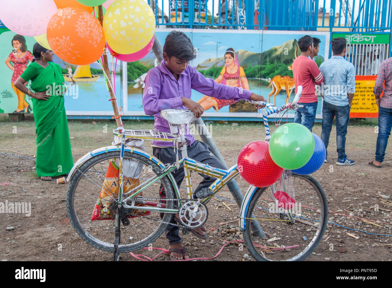 A poor boy selling balloons from his bicycle in mela Stock Photo - Alamy