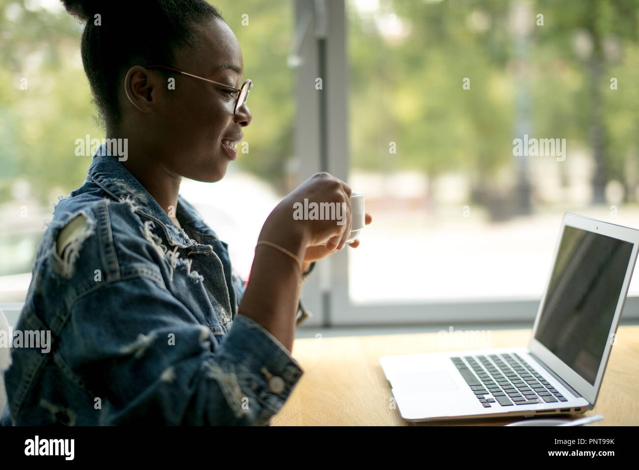 African female blogger, typing a new post during lunchtime at a cafe ...