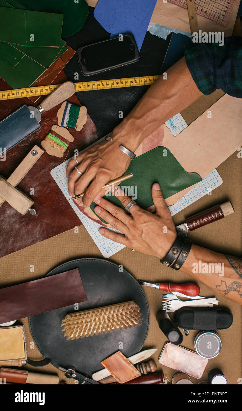 Close up of a shoemaker working with leather sample and hammer at ...