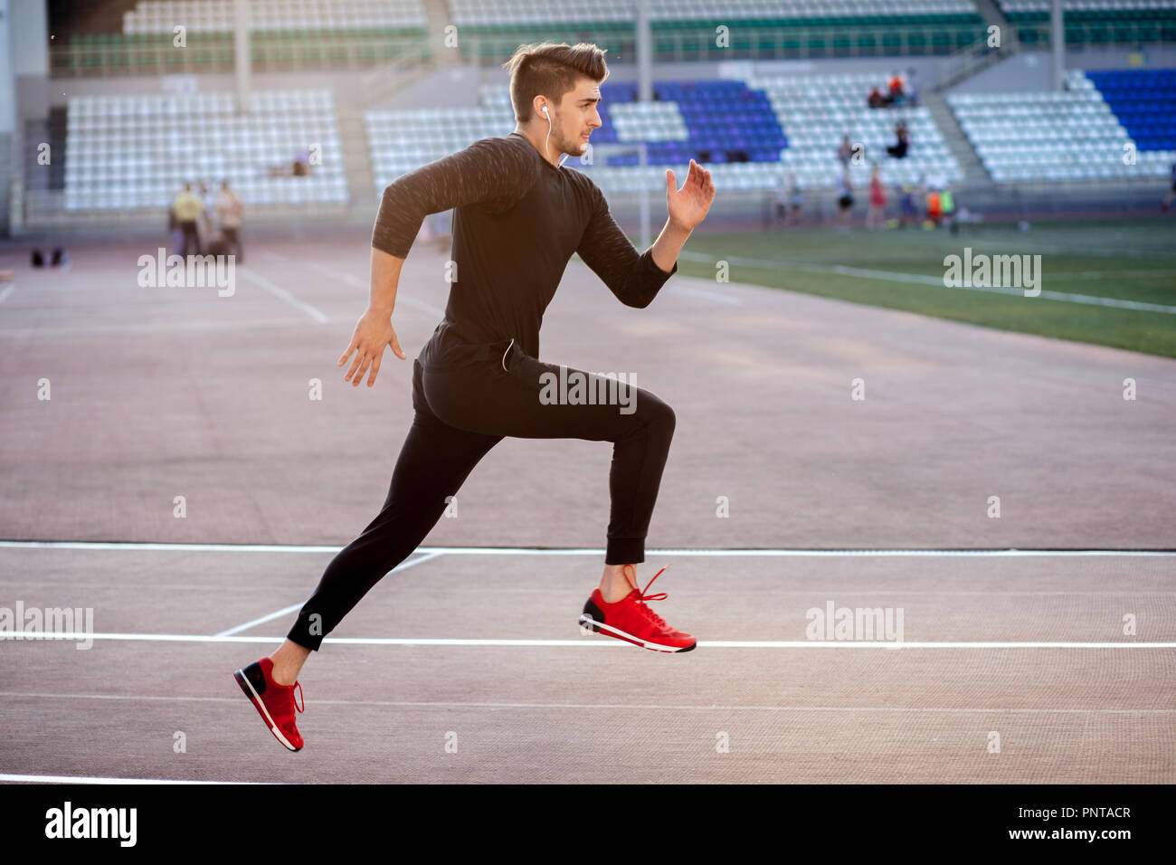 male athlete wearing black sportwear running at track, side view Stock ...