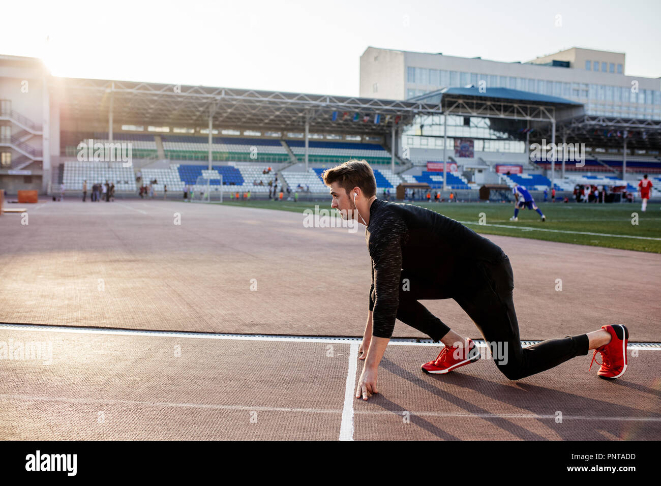 athlete on starting position at running track. Runner practicing run in ...
