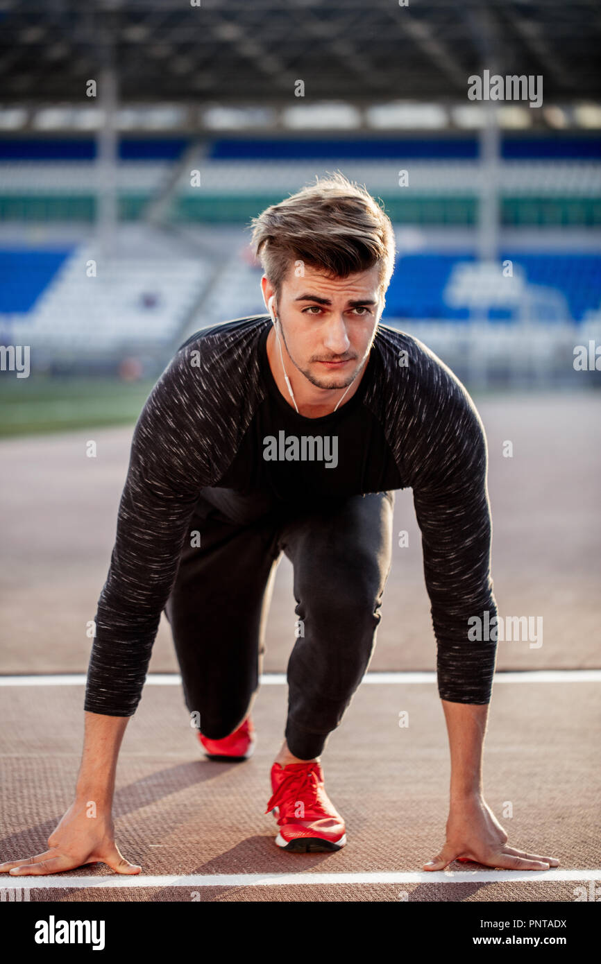 athlete on starting position at running track. Runner practicing run in ...