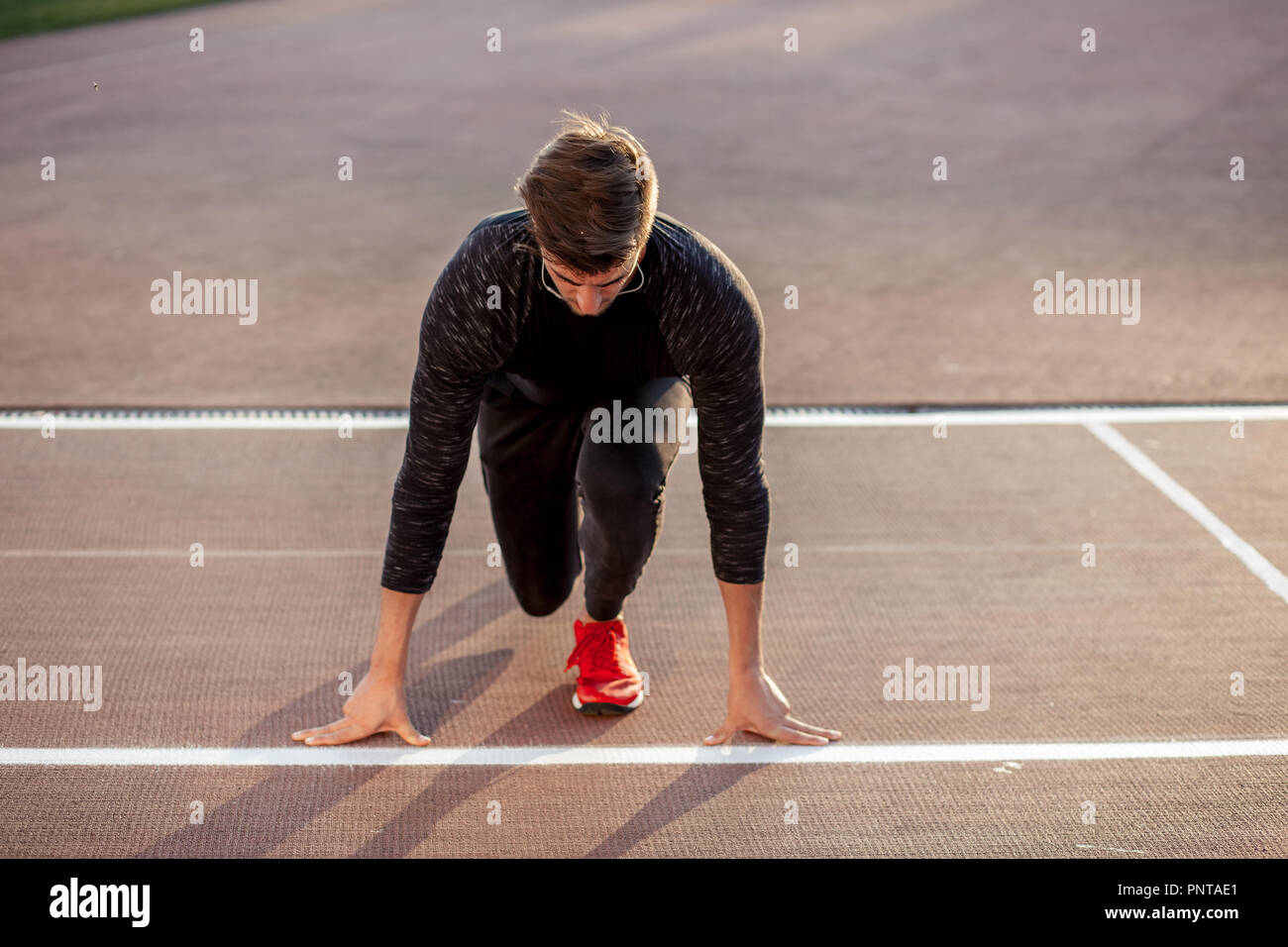 athlete on starting position at running track. Runner practicing run in ...