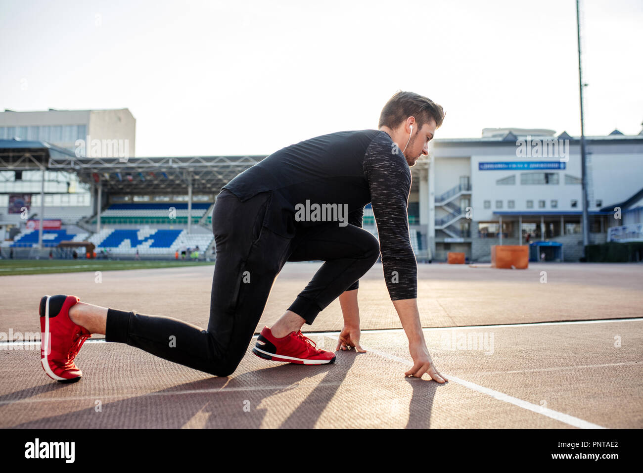 athlete on starting position at running track. Runner practicing run in ...