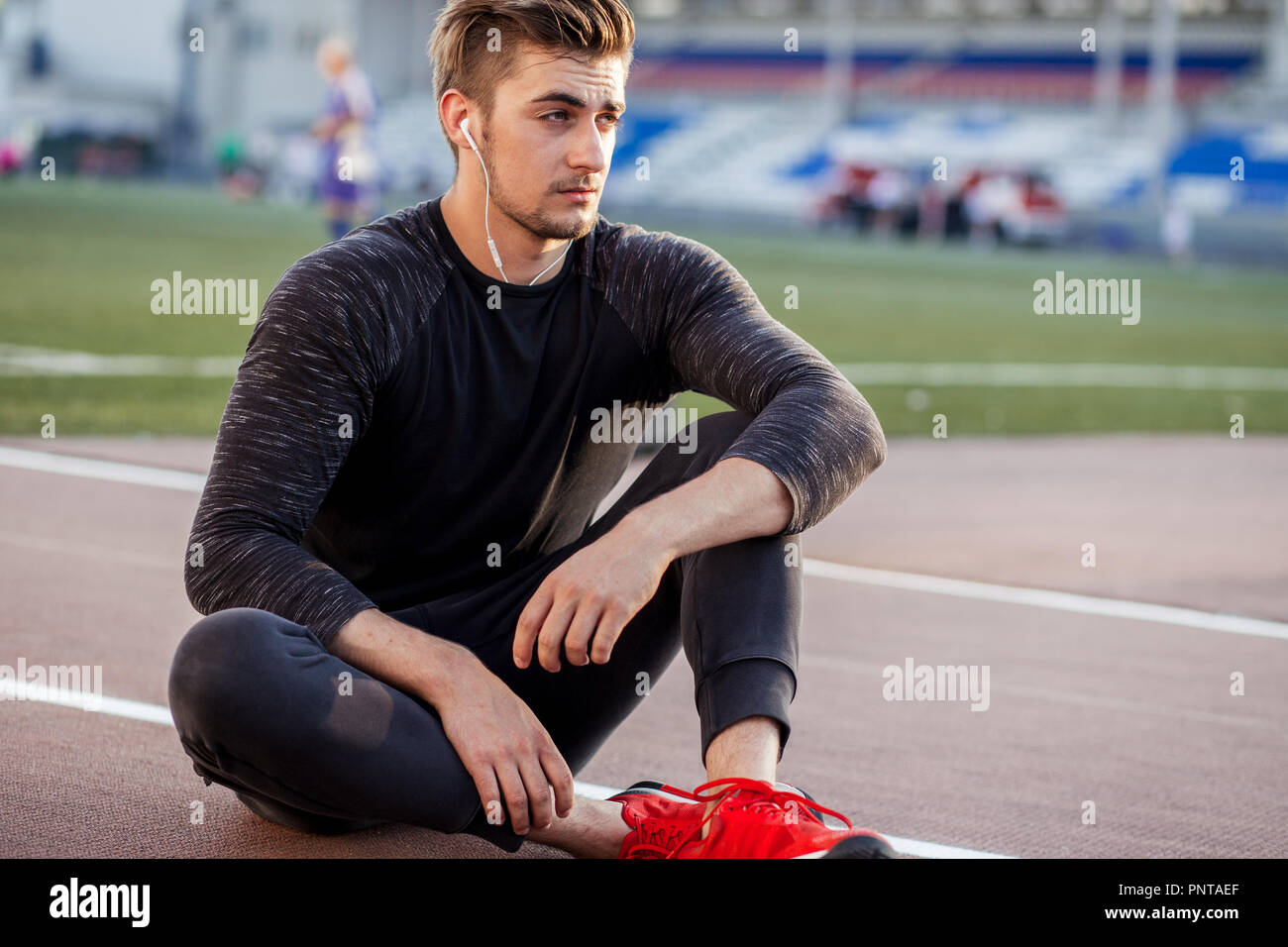 time to rest. man resting after running on track in stadium Stock Photo ...