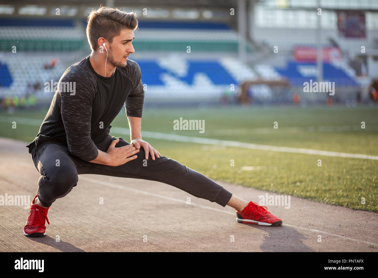 man stretches the body before running on race track in stadium Stock ...